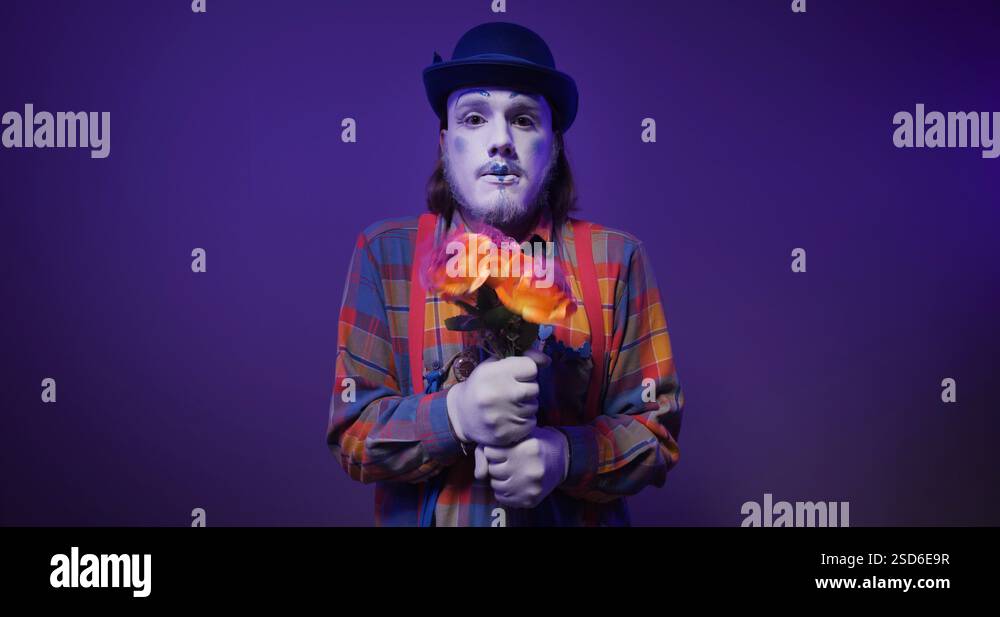 Handsome colorful charismatic mime clown in a hat making trembling ...