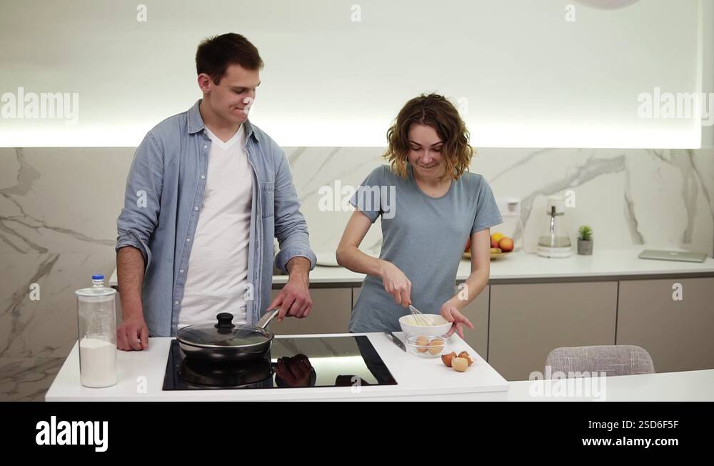 Joyful couple cooking together in domestic kitchen. Positive pretty ...