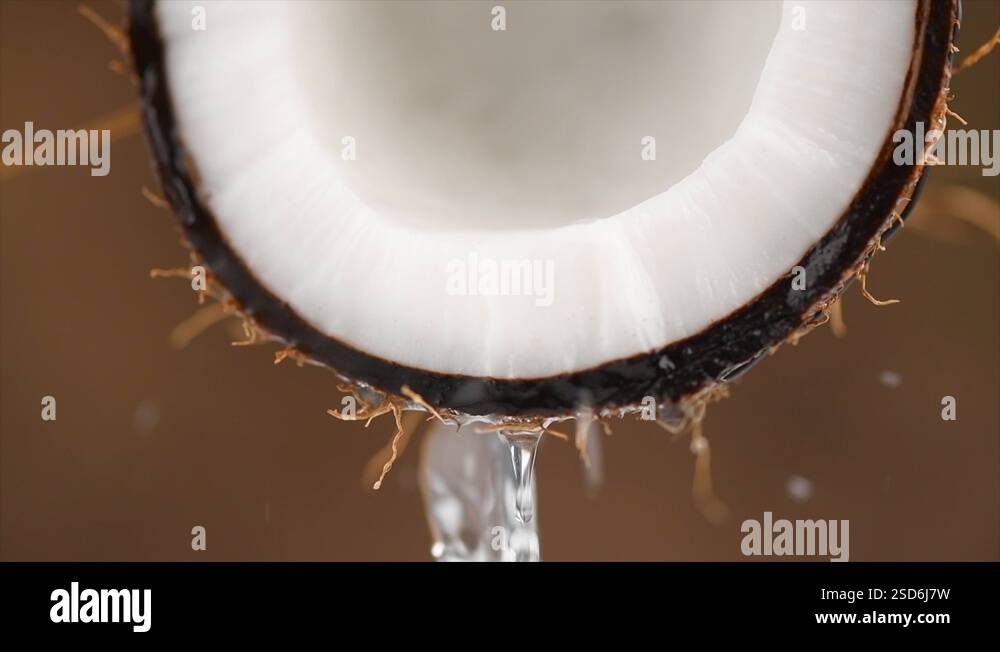 Coconut pouring water, dripping coconut milk, drops of coco nuts oil ...