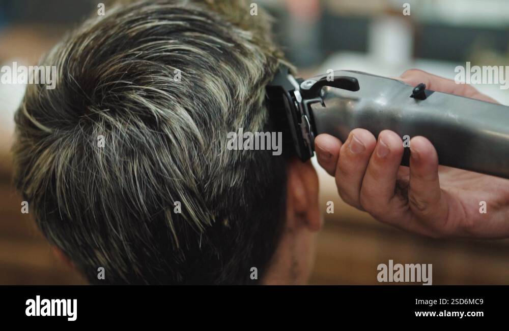 Slow motion close up of a barber's hand giving a haircut to a male ...