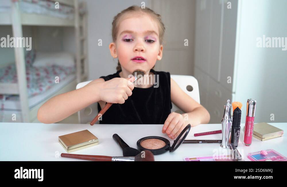 Little girl doing the makeup yourself at home with a highlighter ...