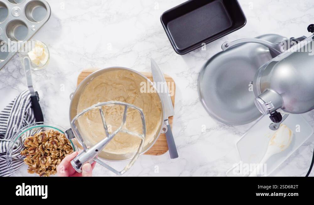 Mixing ingredients together into a metal mixing bowl to bake banana ...
