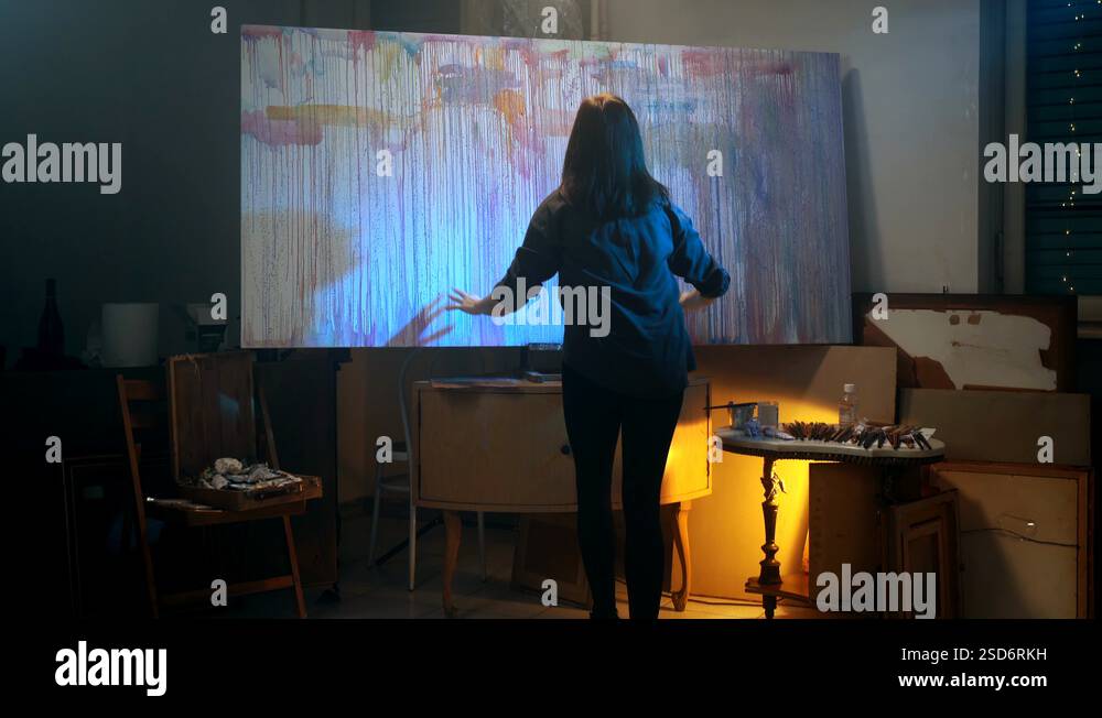 Talented female artist drawing emotionally with hands on big canvas in ...