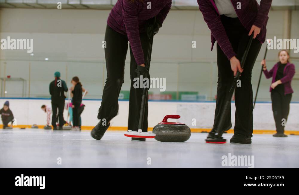 Curling training indoors - leading granite stone on the ice - two women ...