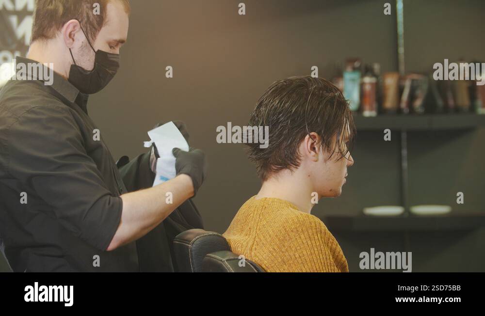 Barber putting on a neck protection on his client in barbershop Stock ...