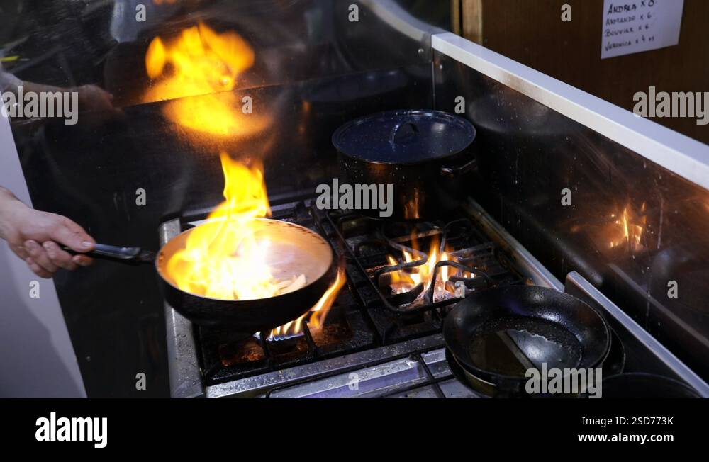 Chef cooking vegetables in wok pan with hard fire burning in slow ...
