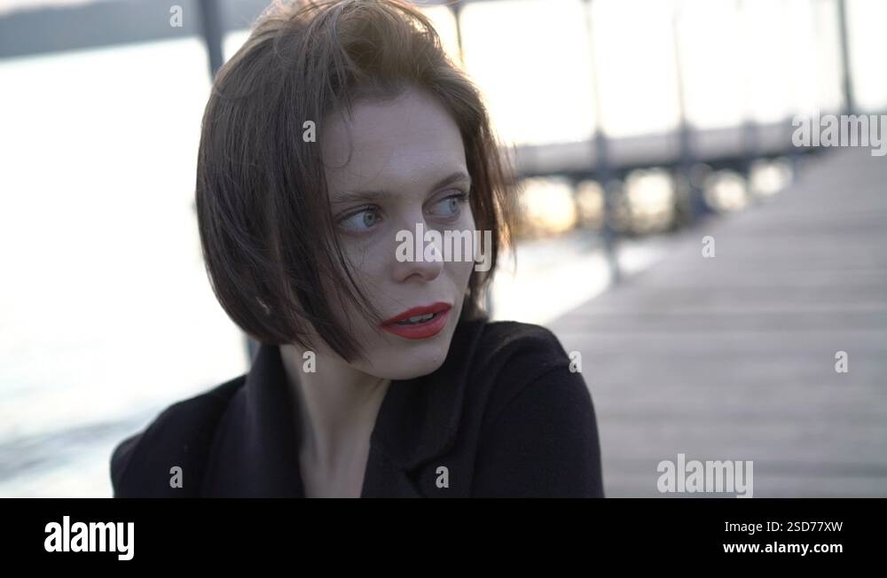 Beautiful woman with windy hair looking aside and smile at camera near ...