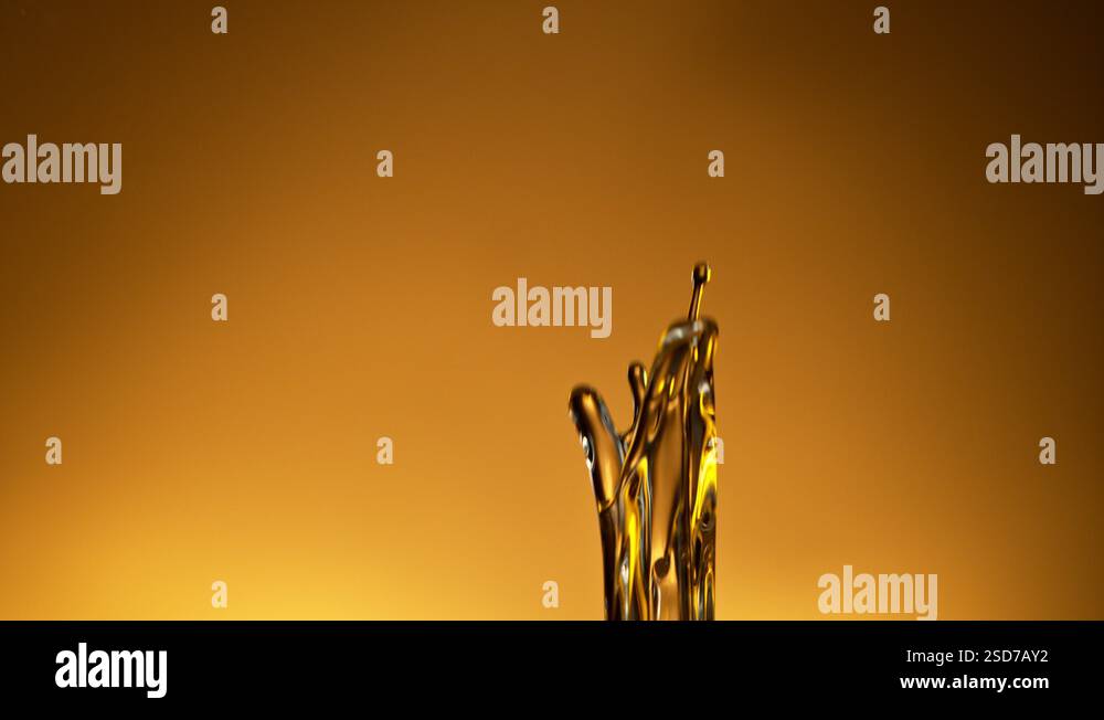 Super Slow Motion Shot of Splashing Oil on Golden Background at 1000fps ...