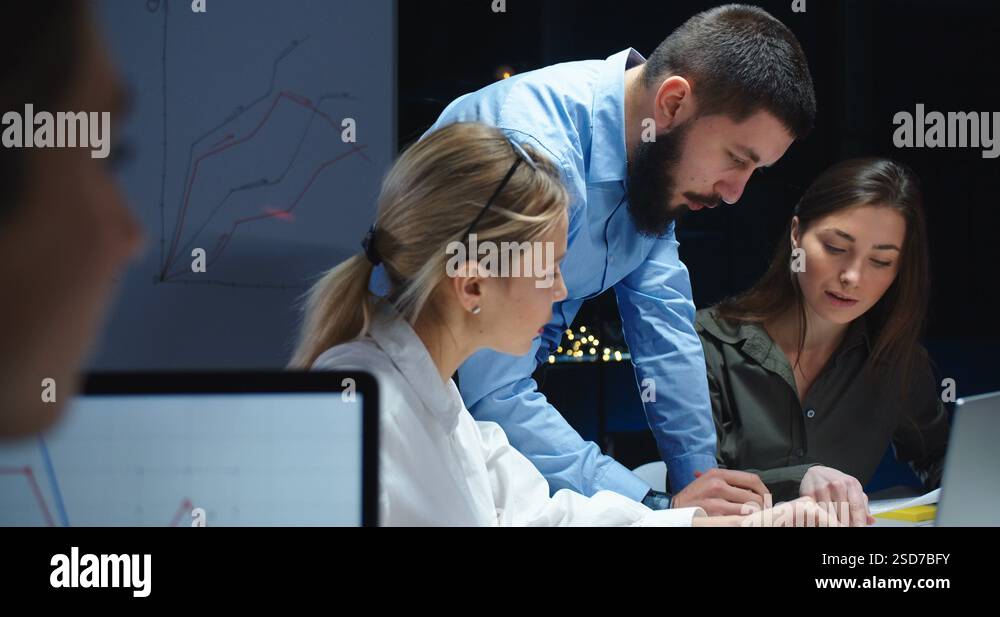 Caucasian male boss checking work of two women office workers and ...