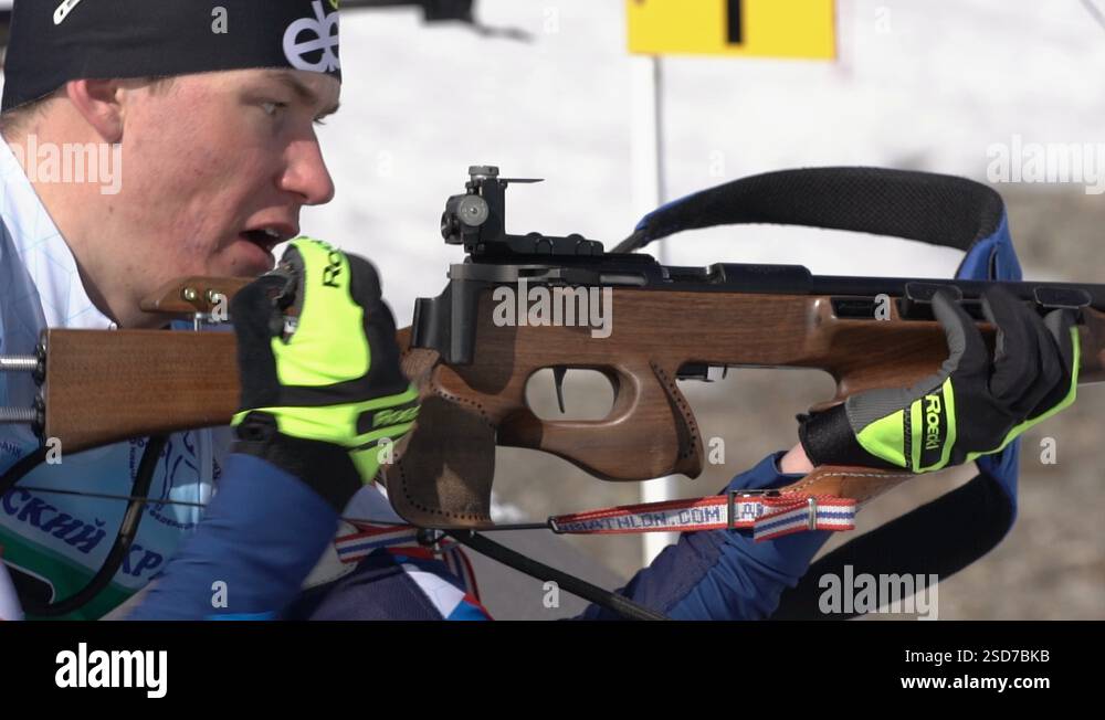 Biathlete aiming, rifle shooting, reloading rifle in prone position ...