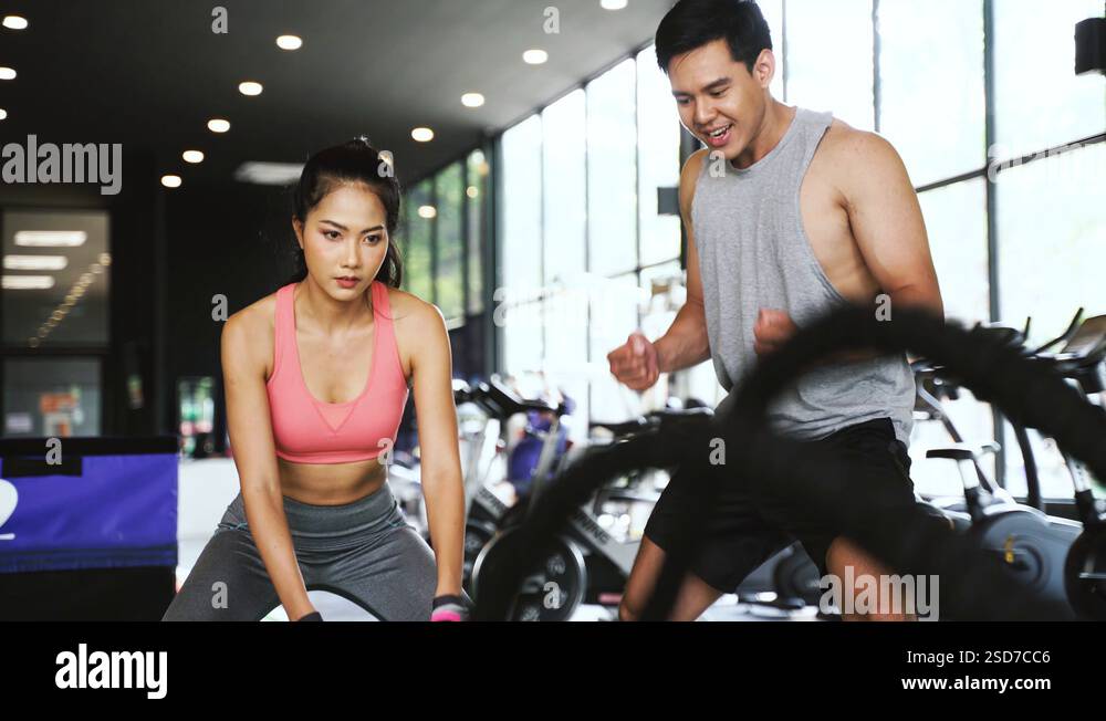 Asian personal trainer coaching a bodybuilding woman to perform crossfit battle Stock Video ...