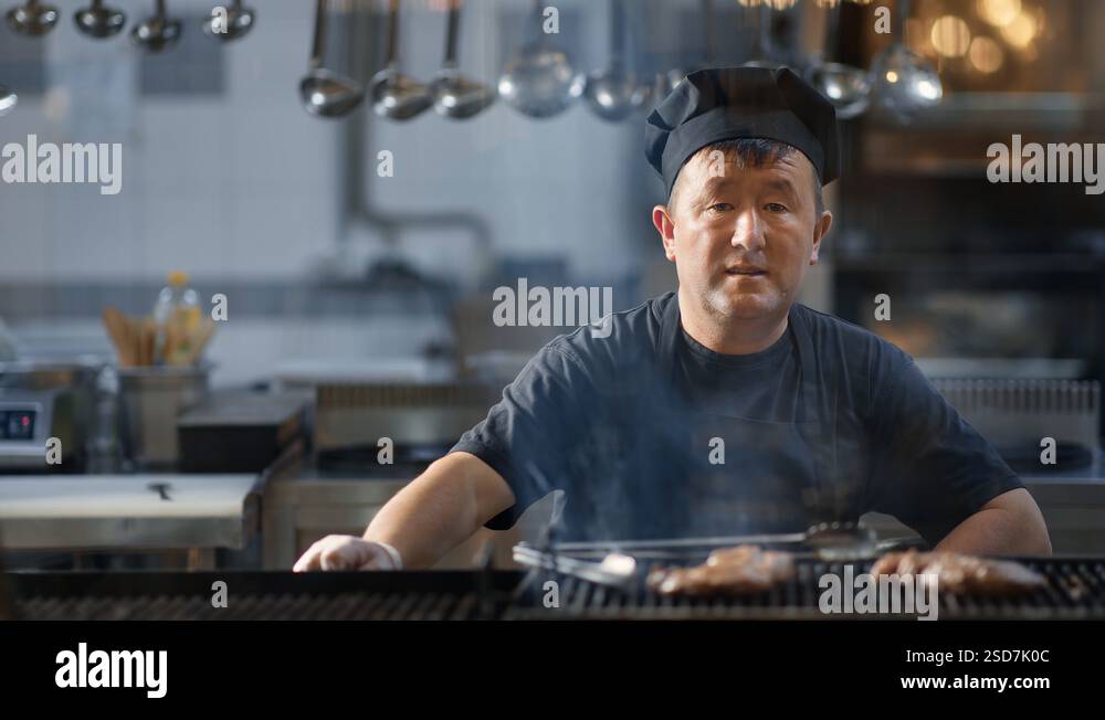 Portrait of smiling Asian chef in uniform posing at kitchen. Medium ...