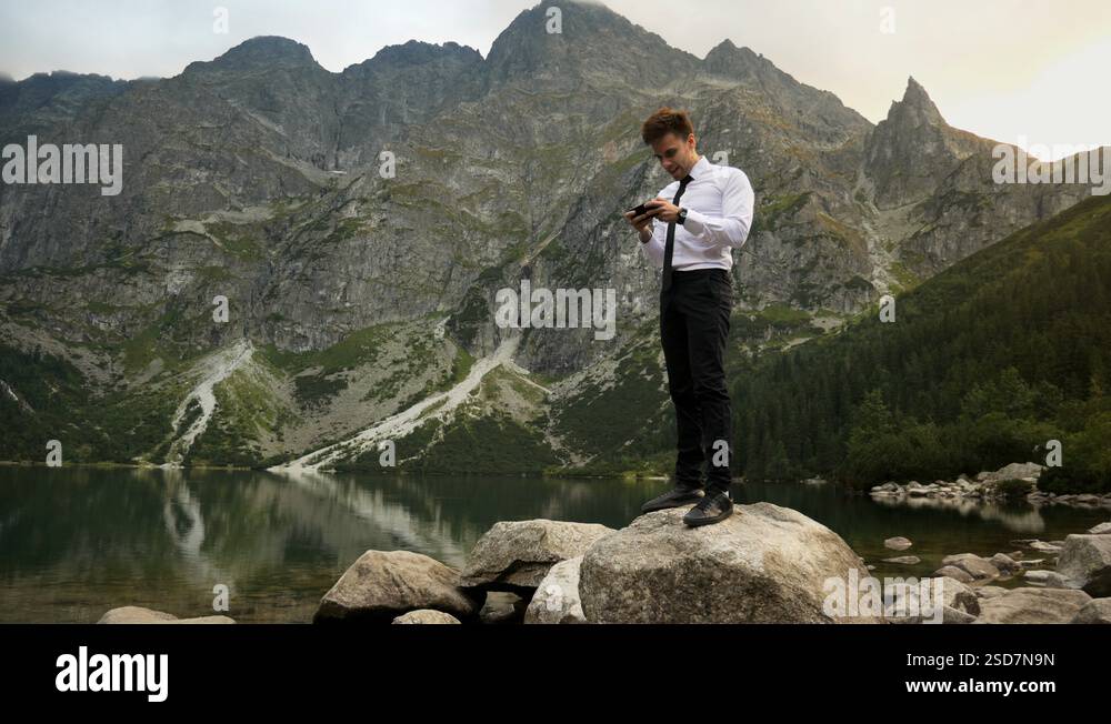 Portrait of successful confident businessman uses a mobile phone near a lake in Stock Video ...