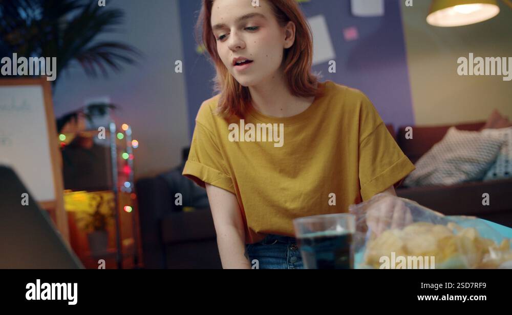 Pretty Caucasian girl enjoying eating junky food and watching movie ...