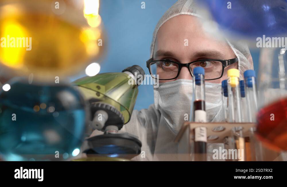 Scientist drops red liquid from pipette into beaker, take beaker with ...