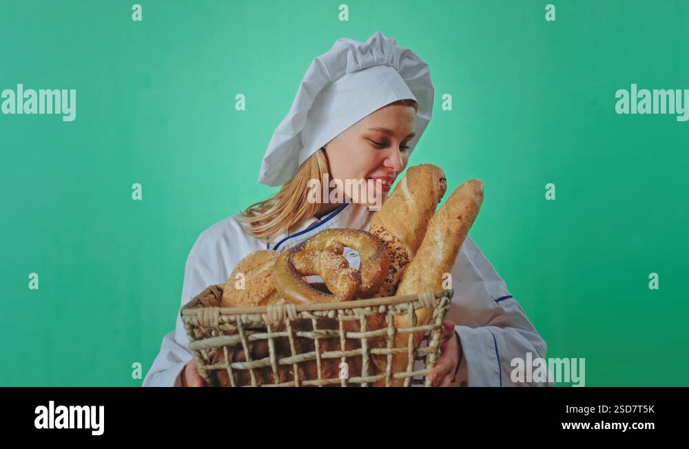 Pretty female baker smelling with love fresh bread froth the basket in ...