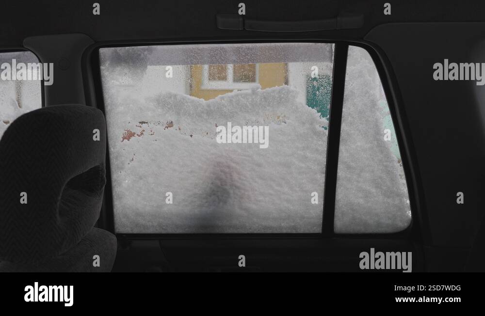 Cleaning the side window of the car from snow. A child's hand cleans ...