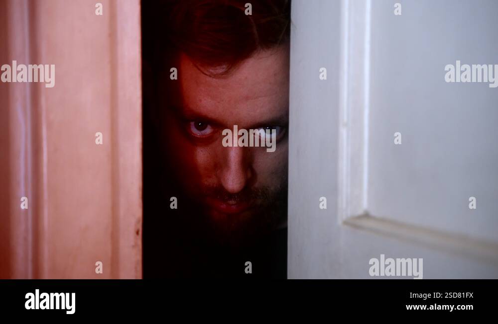 Dangerous serial criminal man hidding his face behind the doors and ...