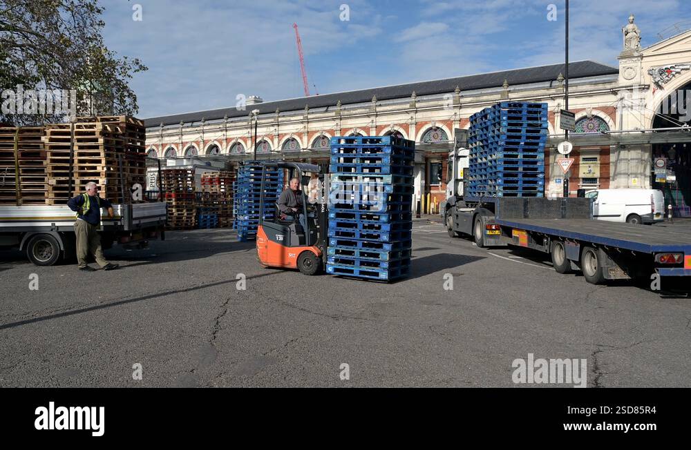 Forklift truck carrying wooden pallets around the back of a lorry ...