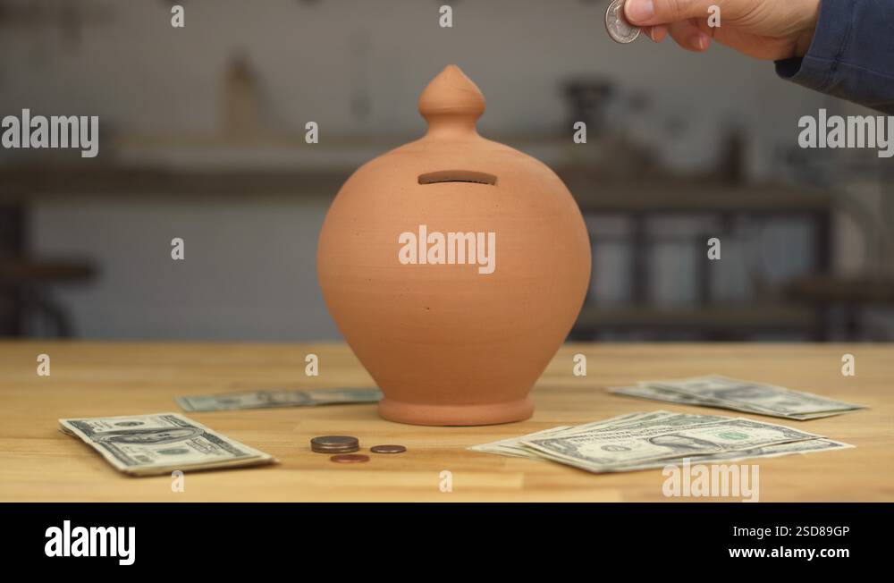 Woman putting coins into a clay money bank with banknotes currency on ...