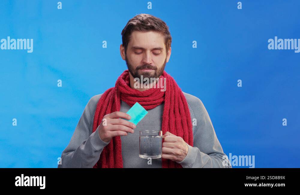 Young sick man in warm scarf taking treatment of cold virus flu pouring ...