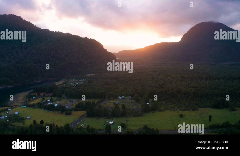 Aerial view of cloudy sunset behind mountains covered with dense native ...