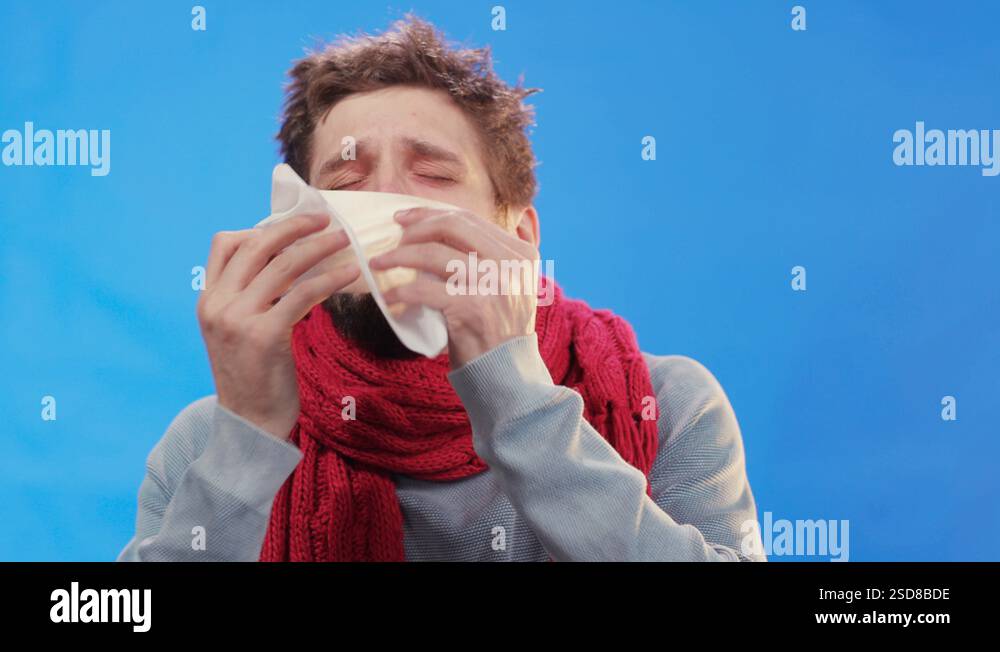 Unhealthy allergic young bearded man sneezing and cleaning nose snot ...