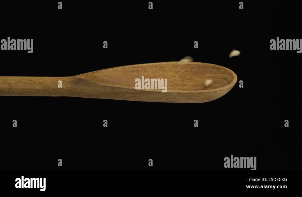 Falling grain pearl barley fills the spoon and fall out of a wooden ...