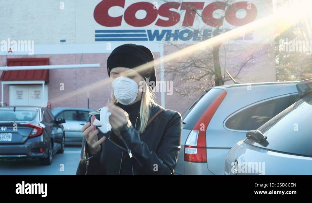 A woman with an N95 respirator mask sanitizes her hands outside of ...