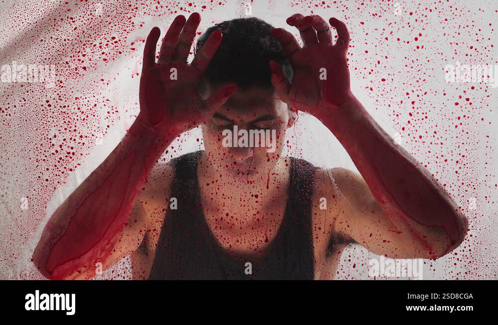 The guy covered in blood standing behind the transparent glass with red ...