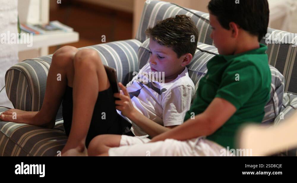 Children staring at tablet screeen playing video-games. Brother ...