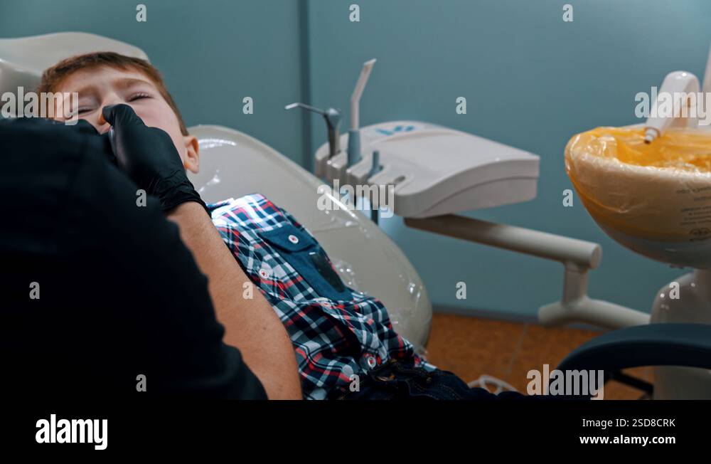 A little stressful boy polishing his teeth in the dentistry and ...