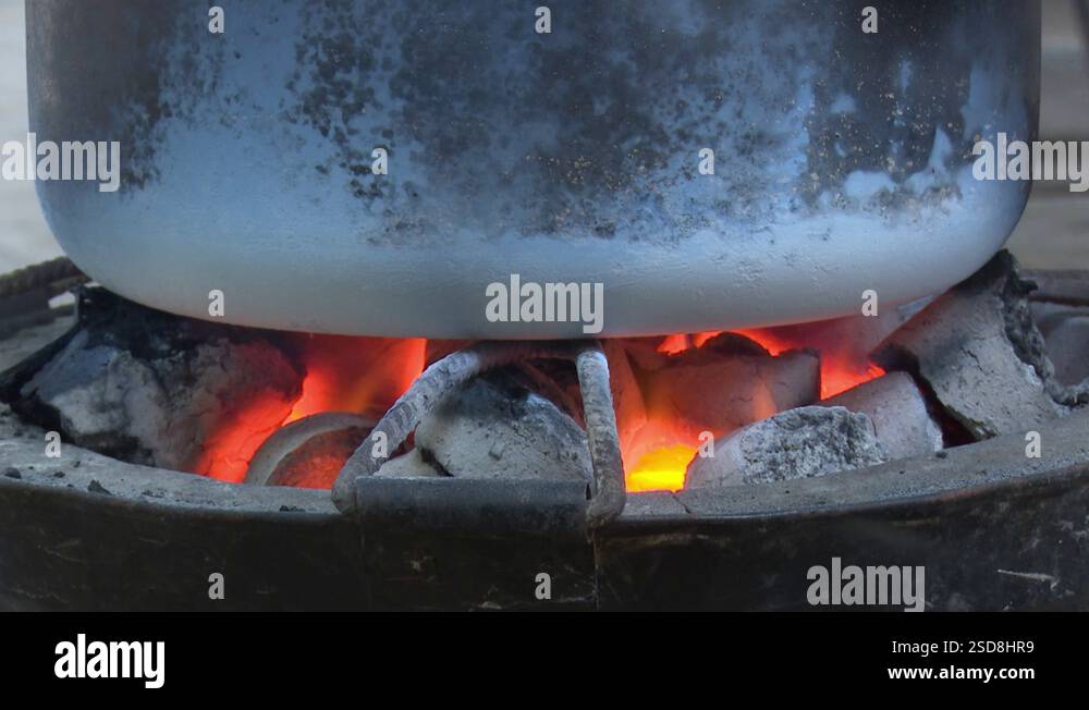 Metal cooking pot on top of coal briquettes, red embers and smoke Stock ...