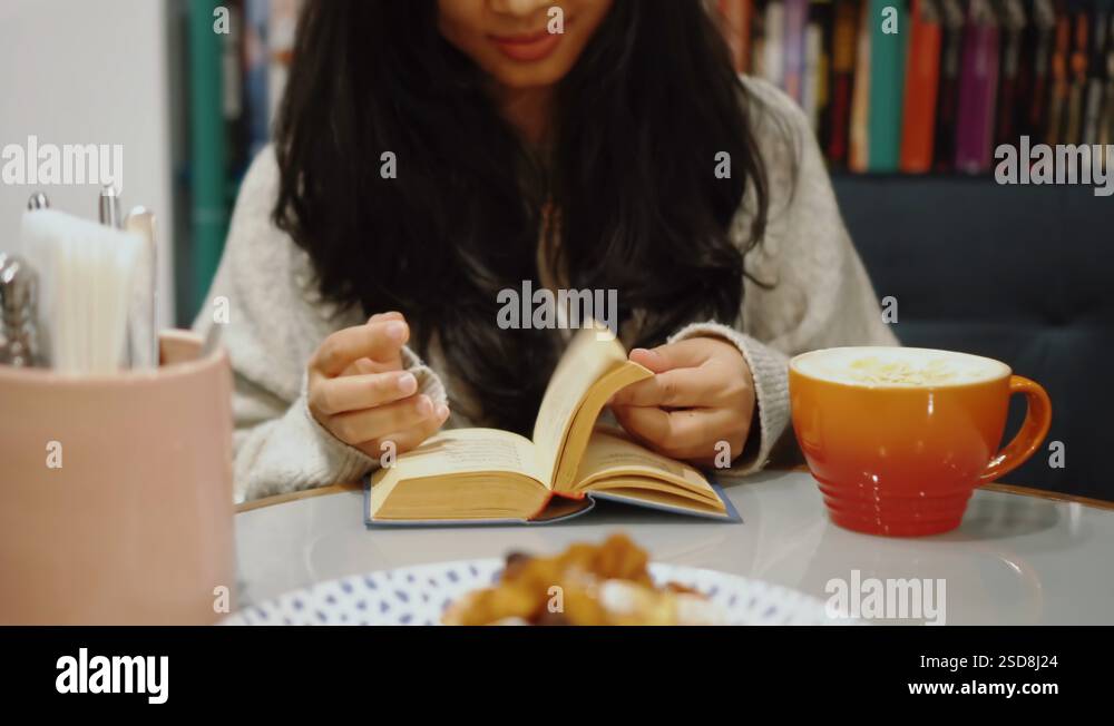 Pretty girl reads book in cafe while drinking coffee. Study in coffee ...
