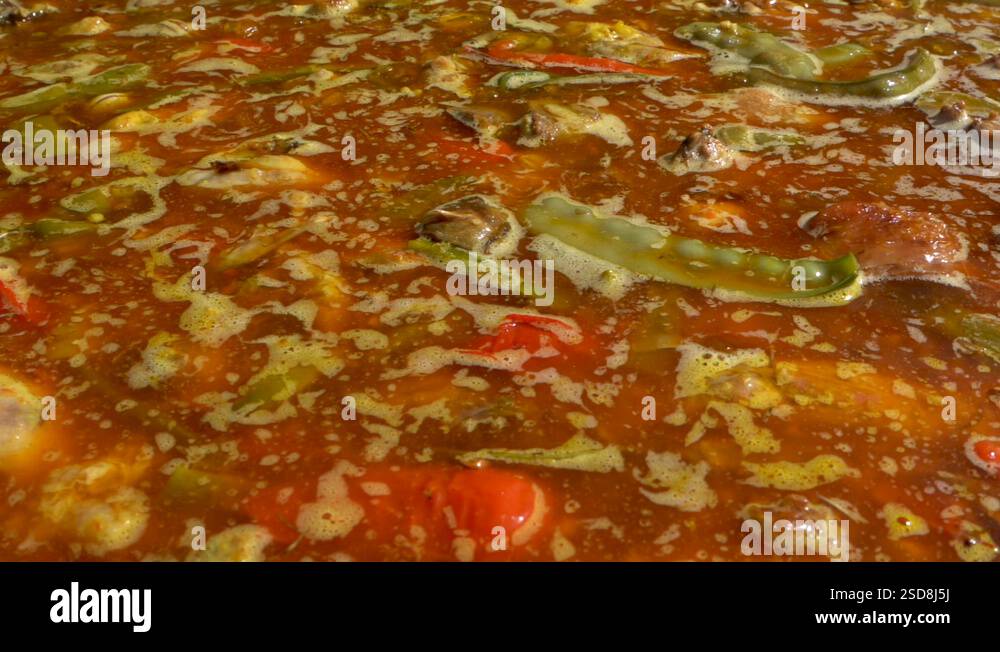 A close up shot of a Spanish Paella being cooked, panning from right to ...