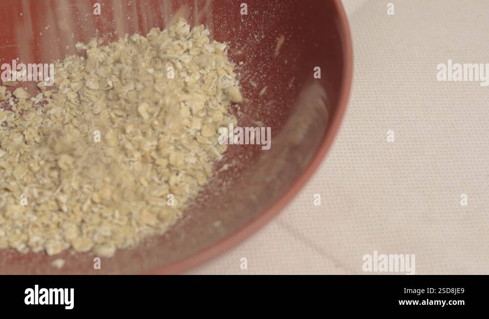 Helping of dry rolled oats pouring into a red bowl Stock Video Footage ...