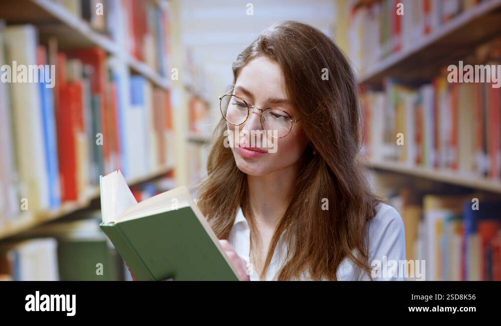 Beautiful inspired young woman in the library reading story book ...