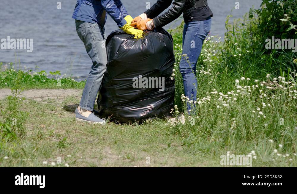 Two girls picking up a garbage in bag. Young women cleaning beach from ...