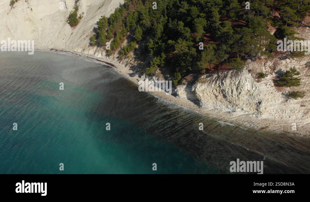 White sedimentary rock and green forest on a sea shore. Transparent sea ...
