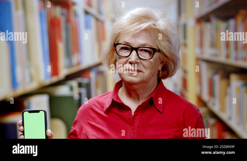 Serious professional woman librarian showing a vertical smartphone ...
