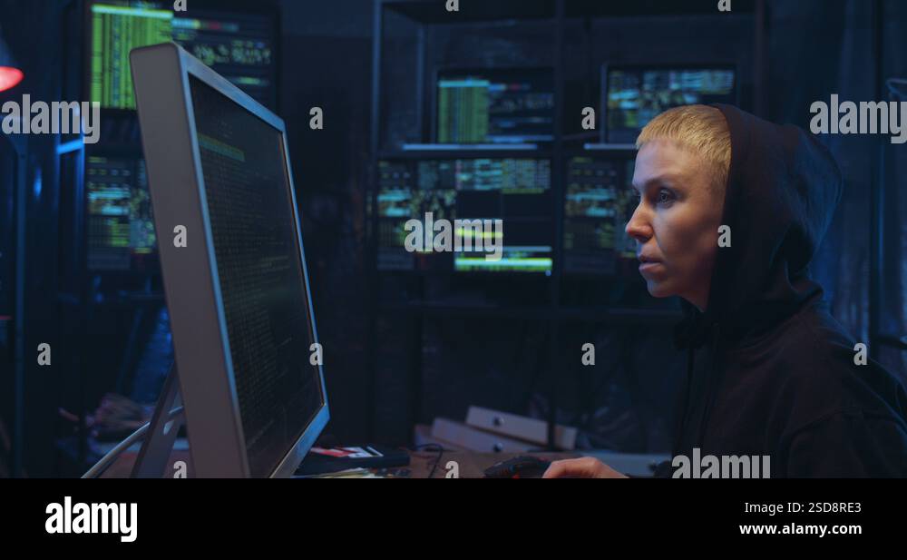 Side view on Caucasian female hacker in black hood typing on keyboard ...