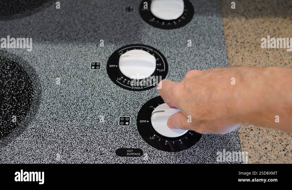 Male hand turning temperature control dial on stove top oven cooking ...