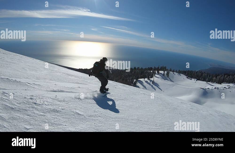 Snowboarder riding freeride on snowboard on snowy downhill on shining ...