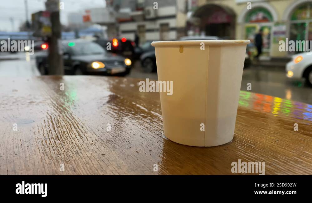 Paper cup of take away espresso coffee on wet table of the street cafe ...