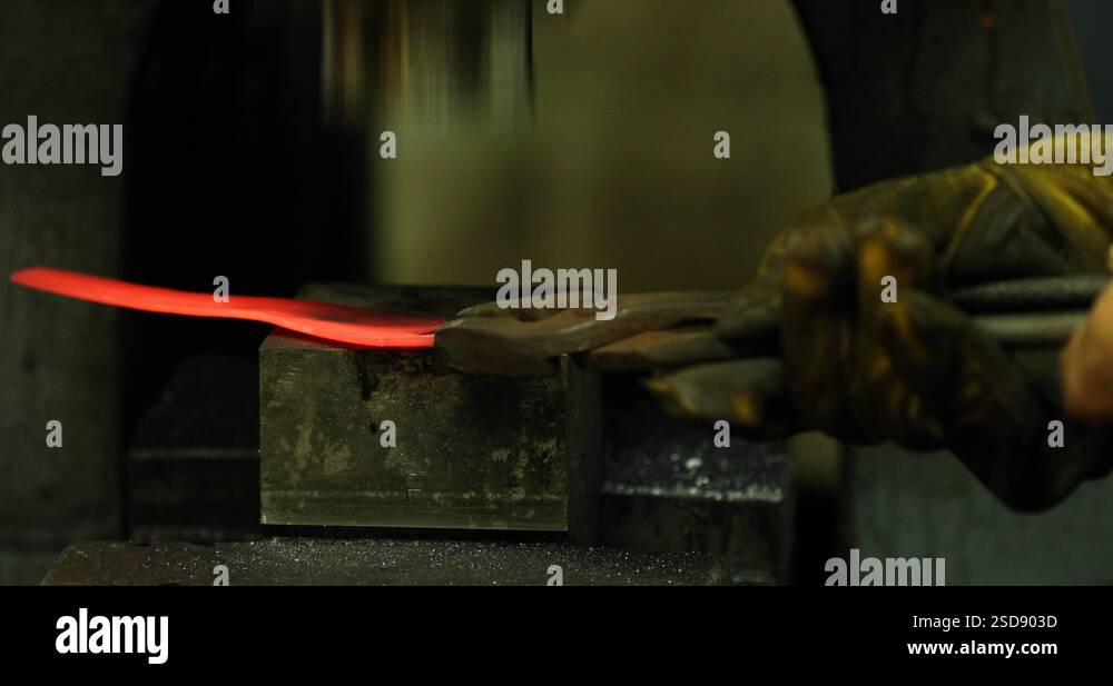 Bladesmith working with hot blade at hydraulic forge hammer Stock Video ...