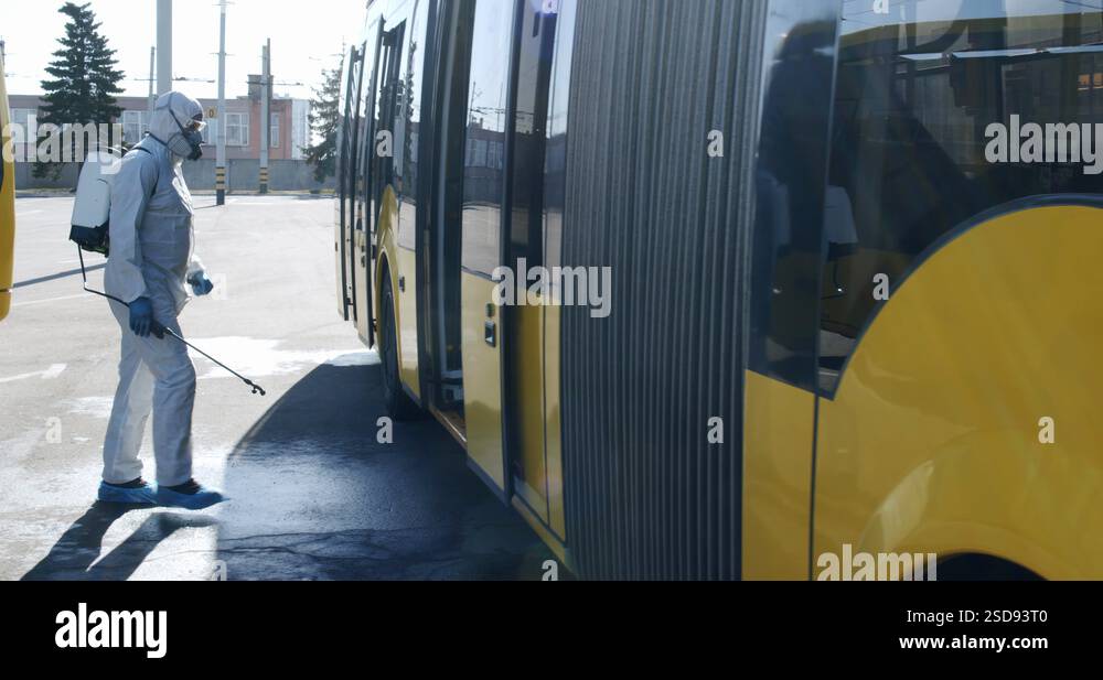 HazMat team in protective suits decontaminating a bus during virus ...