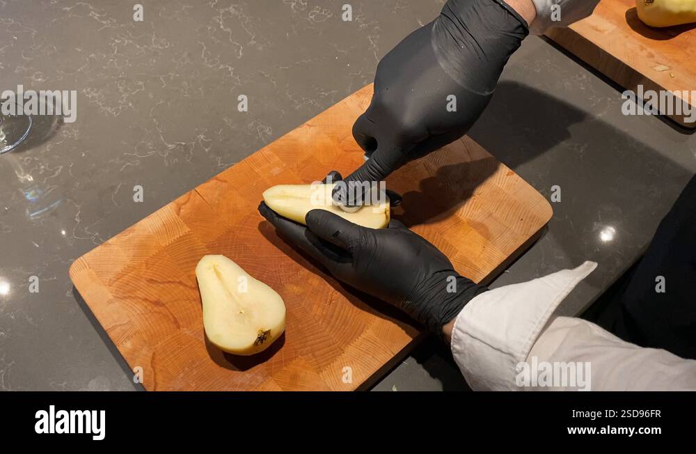 Male chef prepares a dessert of pear and cuts the middle with a bone ...