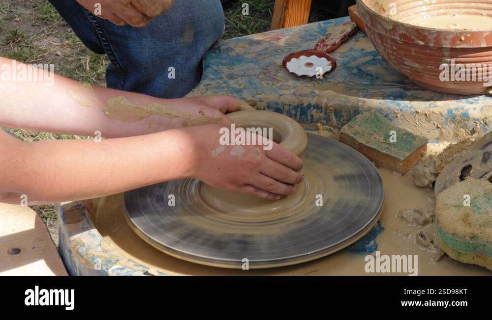 Traditional potter and boy on a potter's wheel form a pot. They work ...