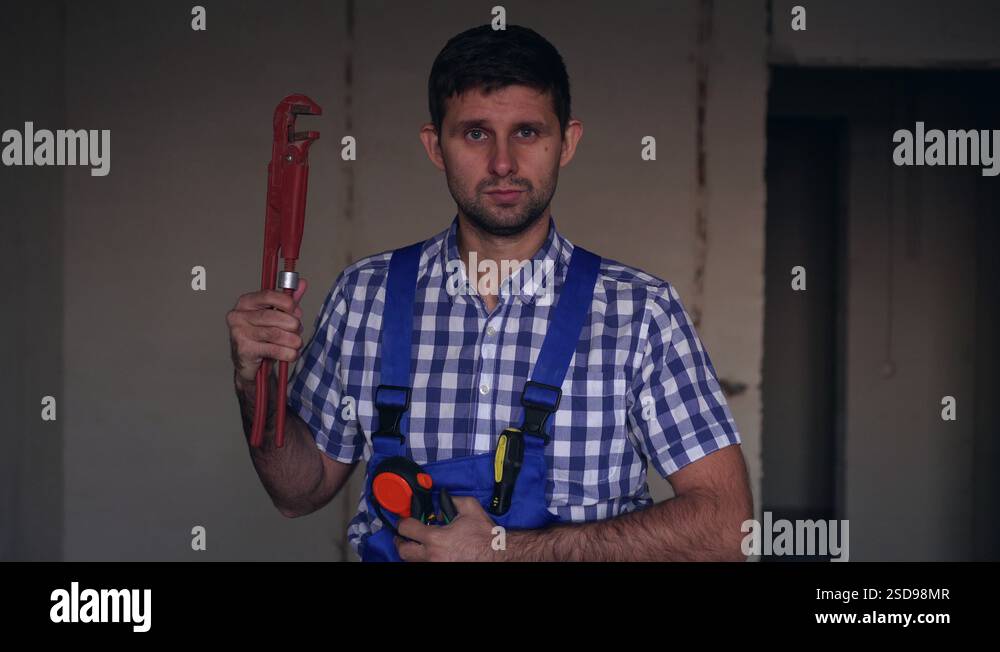 A male plumber with a large plumbing tool. Portrait of a plumber man ...