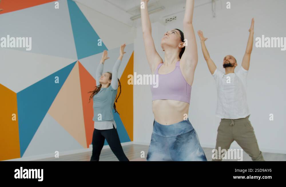 Serious man and women busy with yoga asanas during class in modern ...